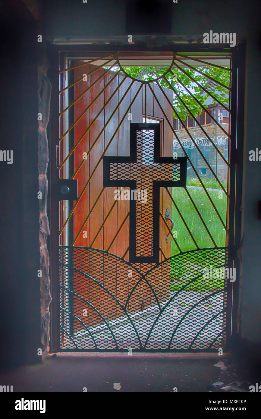 Light coming through metal gate with cross from inside church in prison ...