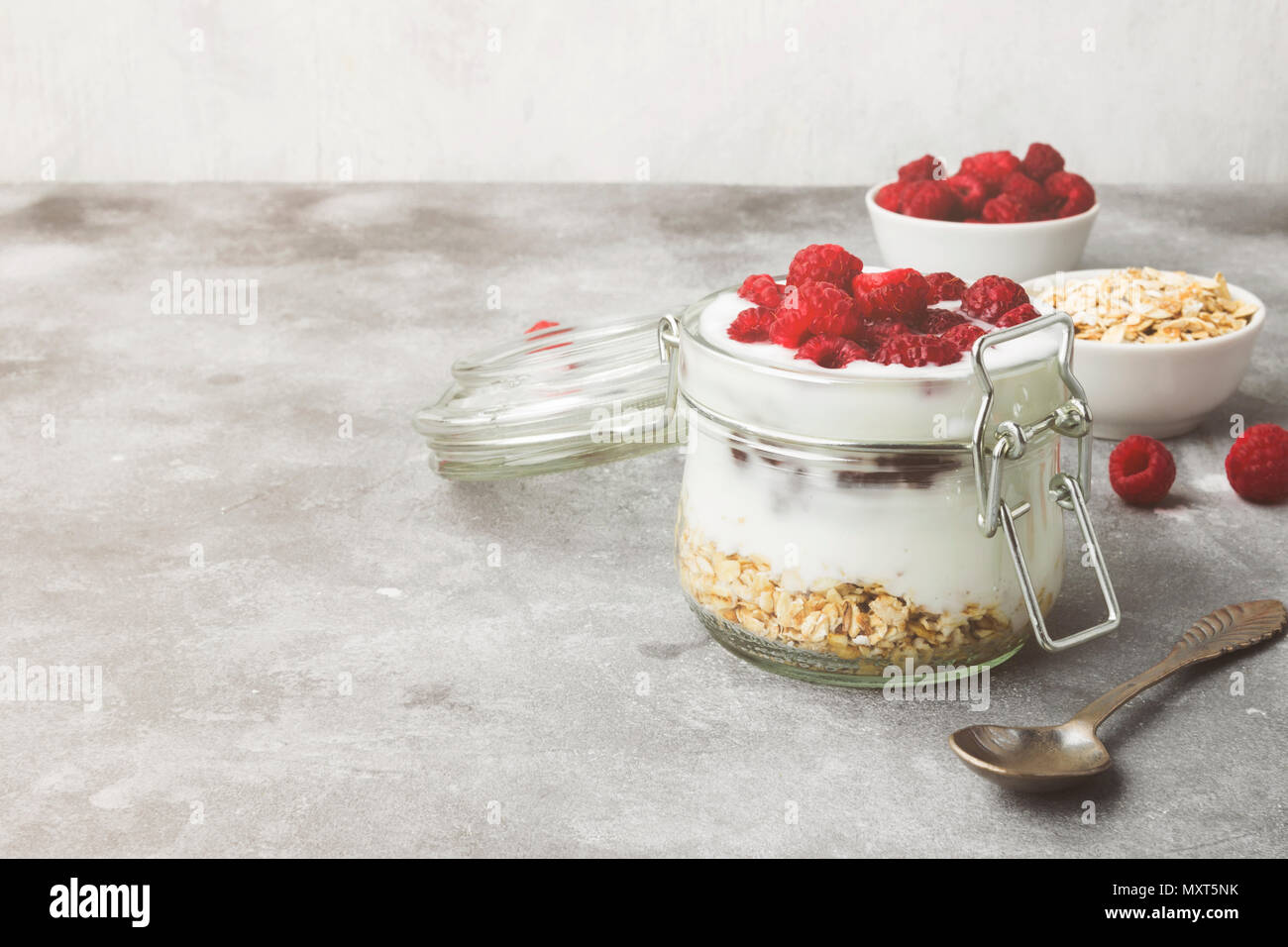 Glanola in glass jar with raspberry on a gray background. Copy space ...