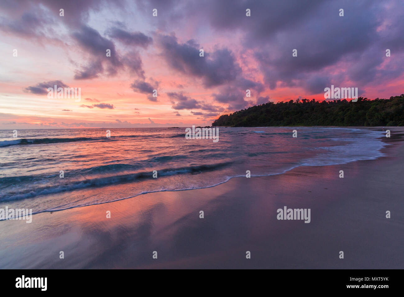 sunset over a tropical beach with palm trees and beautiful crystalline ...