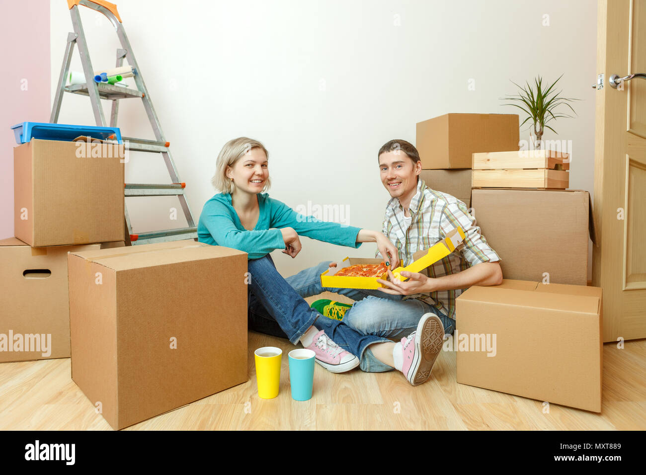 Photos of women and men eating pizza among cardboard boxes Stock Photo ...