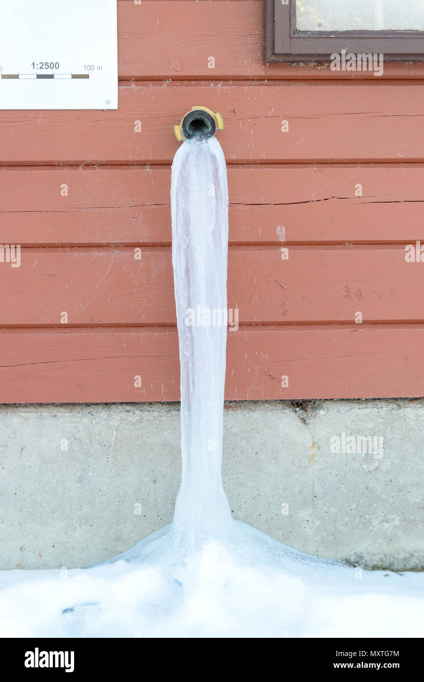 Frozen water drain comming out of a wooden house Stock Photo - Alamy