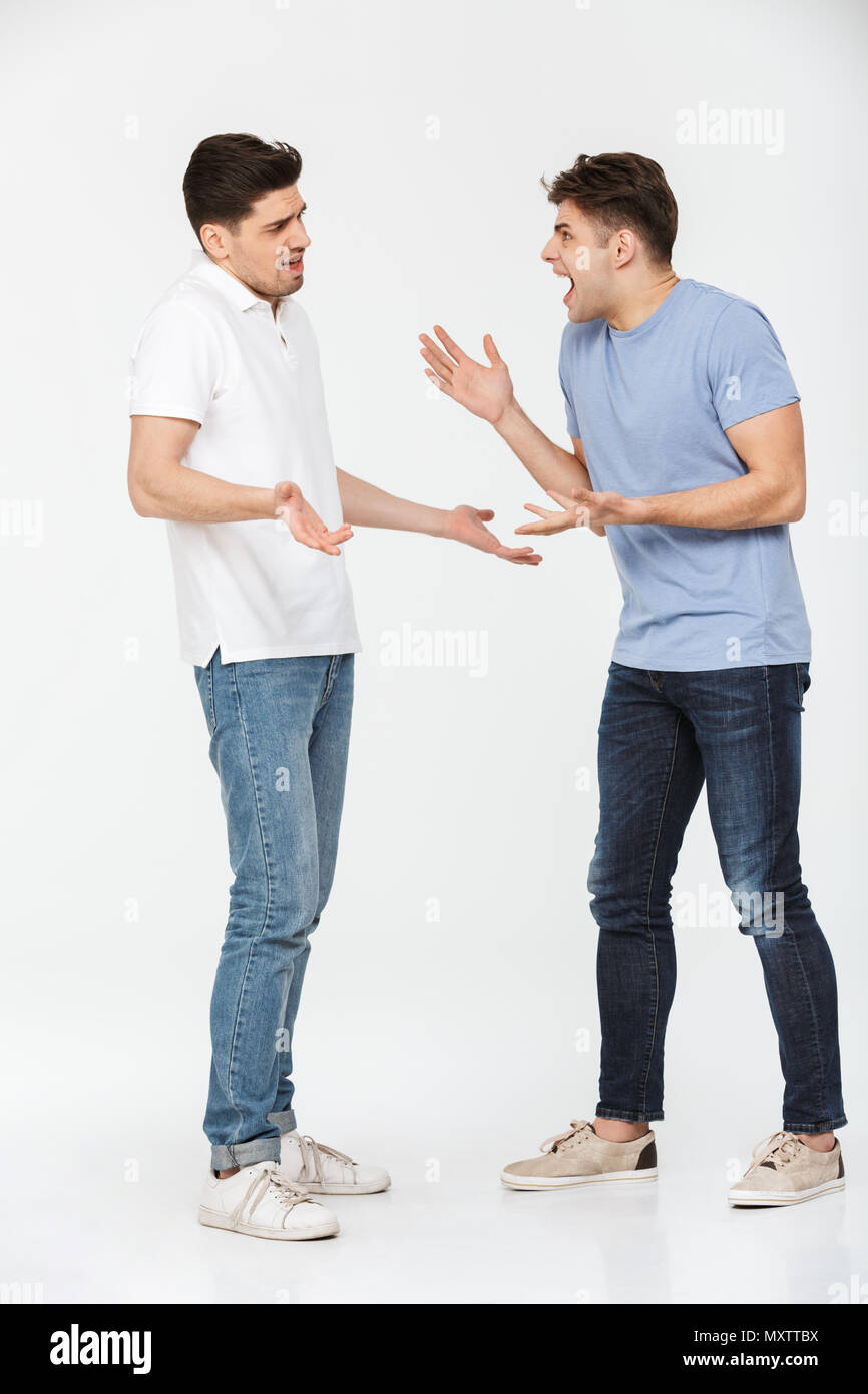 Full Length Portrait Of Two Frustrated Young Men Arguing Isolated Over