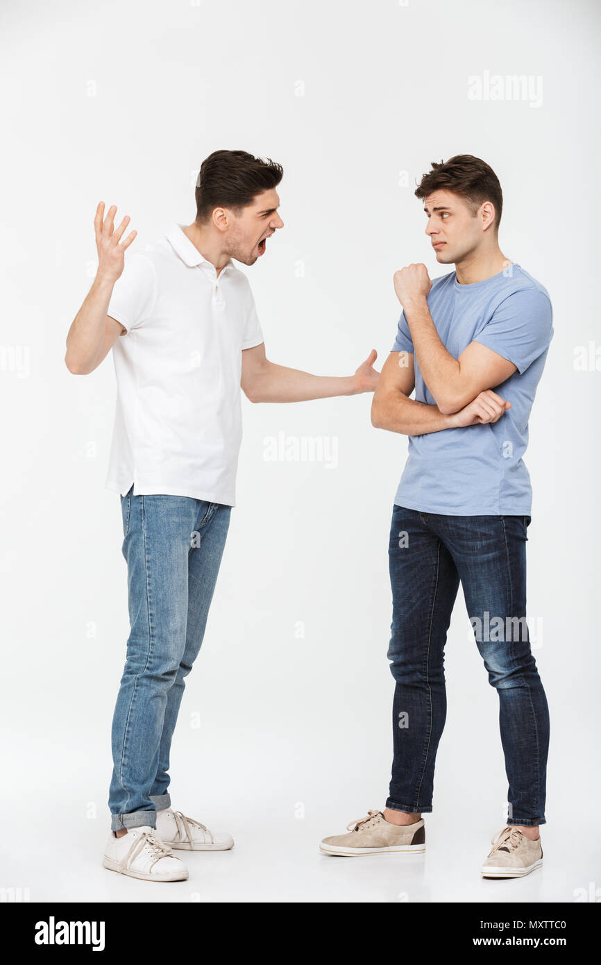 Full length portrait of two angry young men arguing isolated over white ...