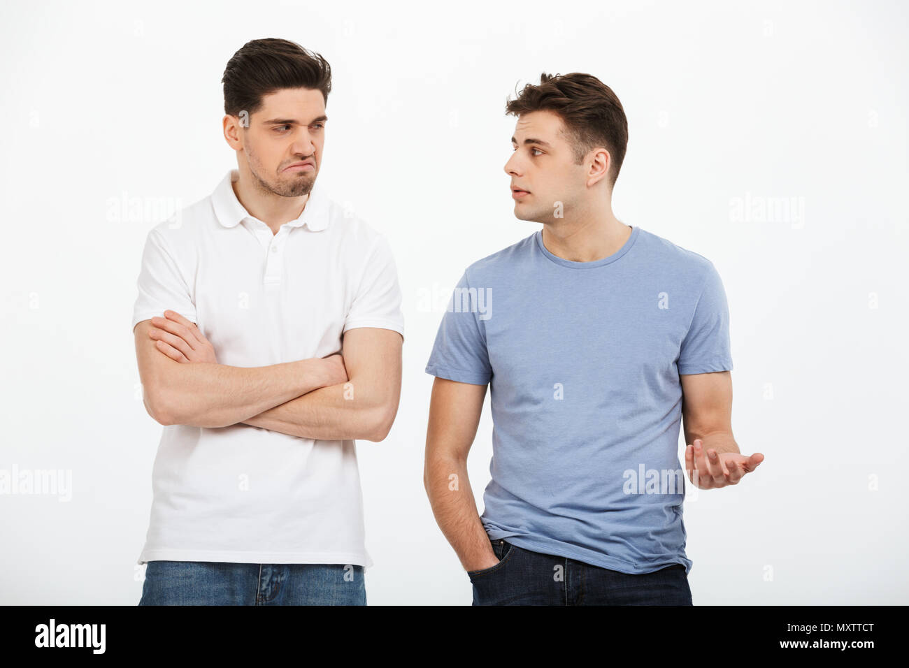 Portrait of two upset young men arguing isolated over white background ...