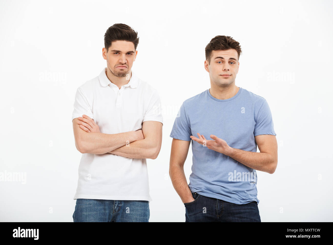 Portrait of two disappointed young men looking at camera isolated over ...