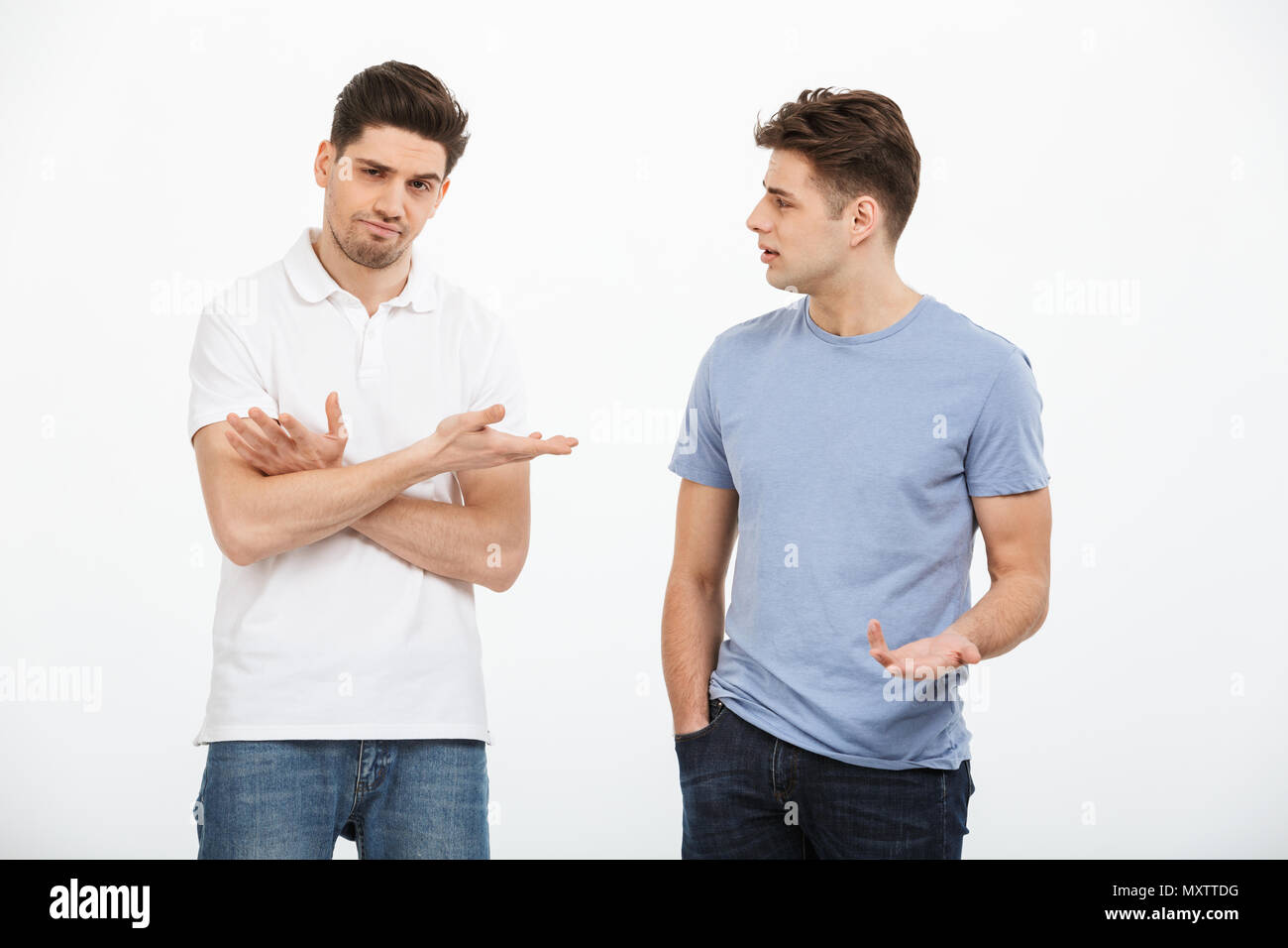 Portrait of two disappointed young men having an argument isolated over ...