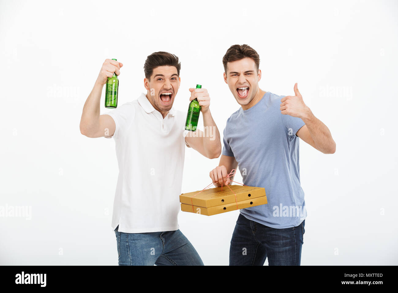 Portrait of two happy young men celebrating while holding beer bottles ...
