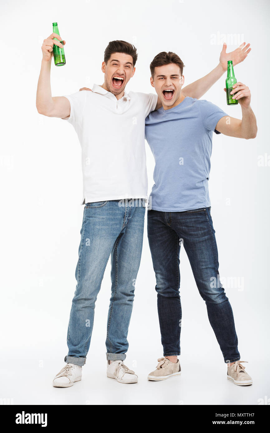 Full length portrait of two happy young men celebrating while holding ...