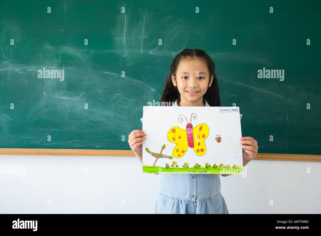 Child girl show paper painting in classroom at chalkboard Stock Photo ...