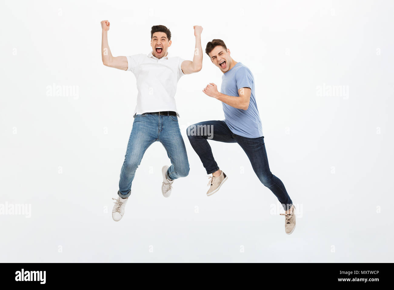 Full length portrait of two excited young men jumping and celebrating ...