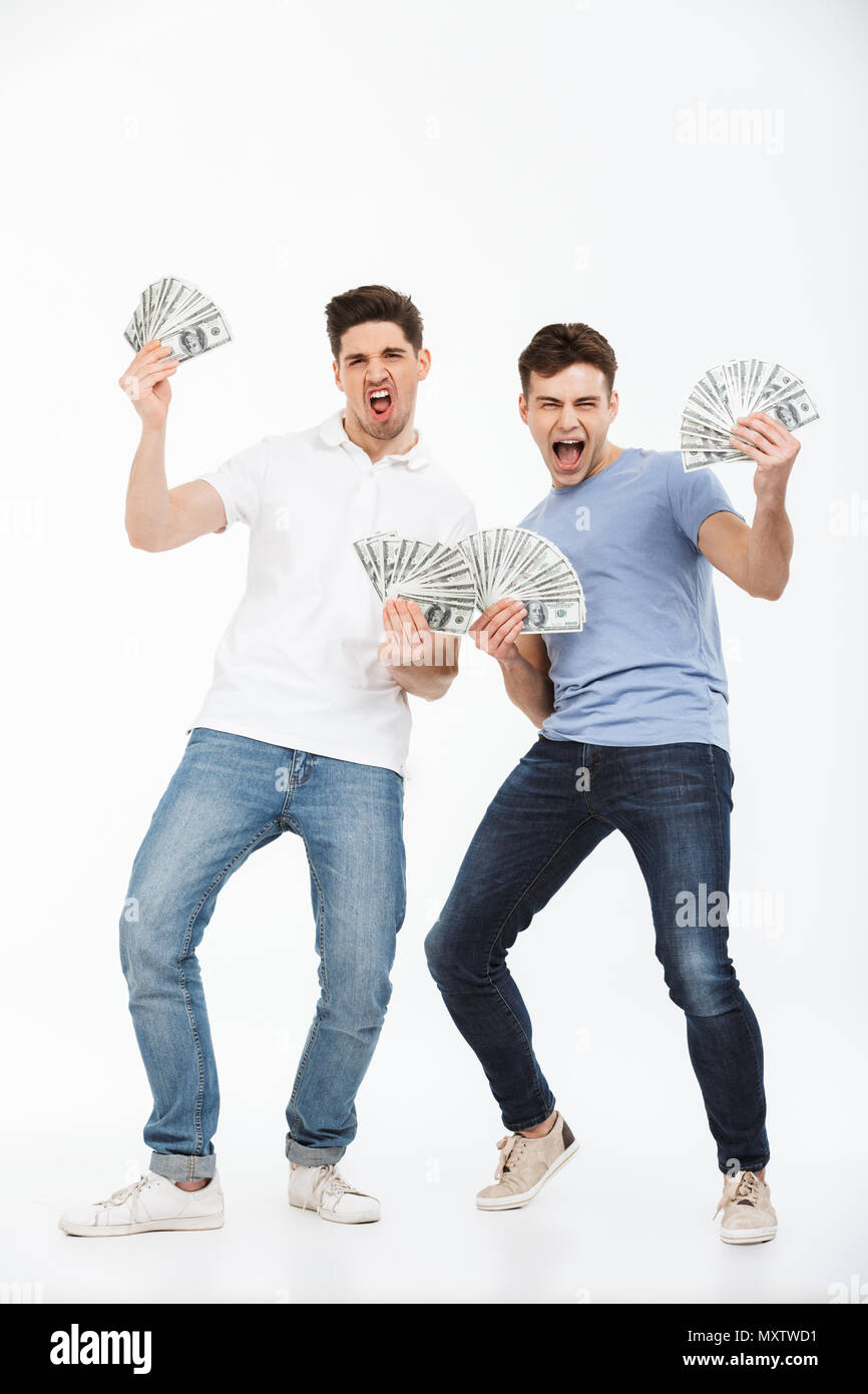 Full length portrait of two happy young men showing money banknotes and ...