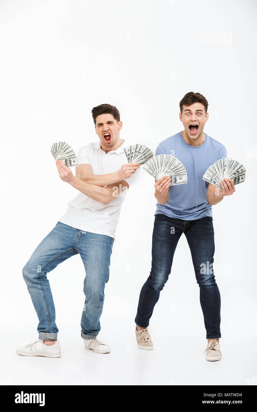 Full length portrait of two cheerful young men showing money banknotes ...