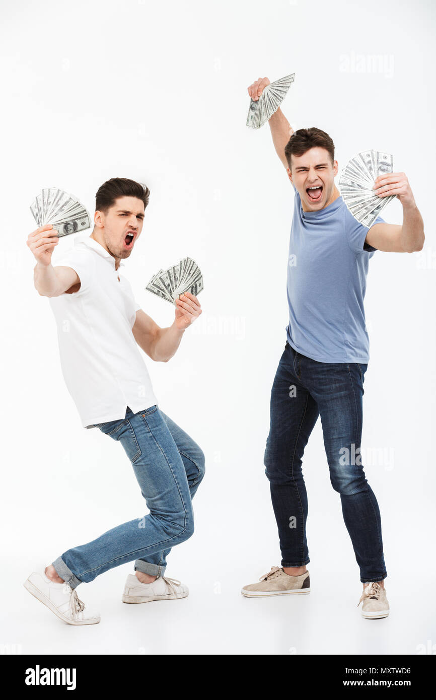 Full length portrait of two excited young men showing money banknotes ...