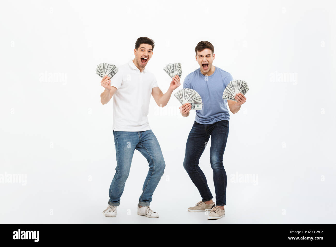 Full length portrait of two joyful young men showing money banknotes ...