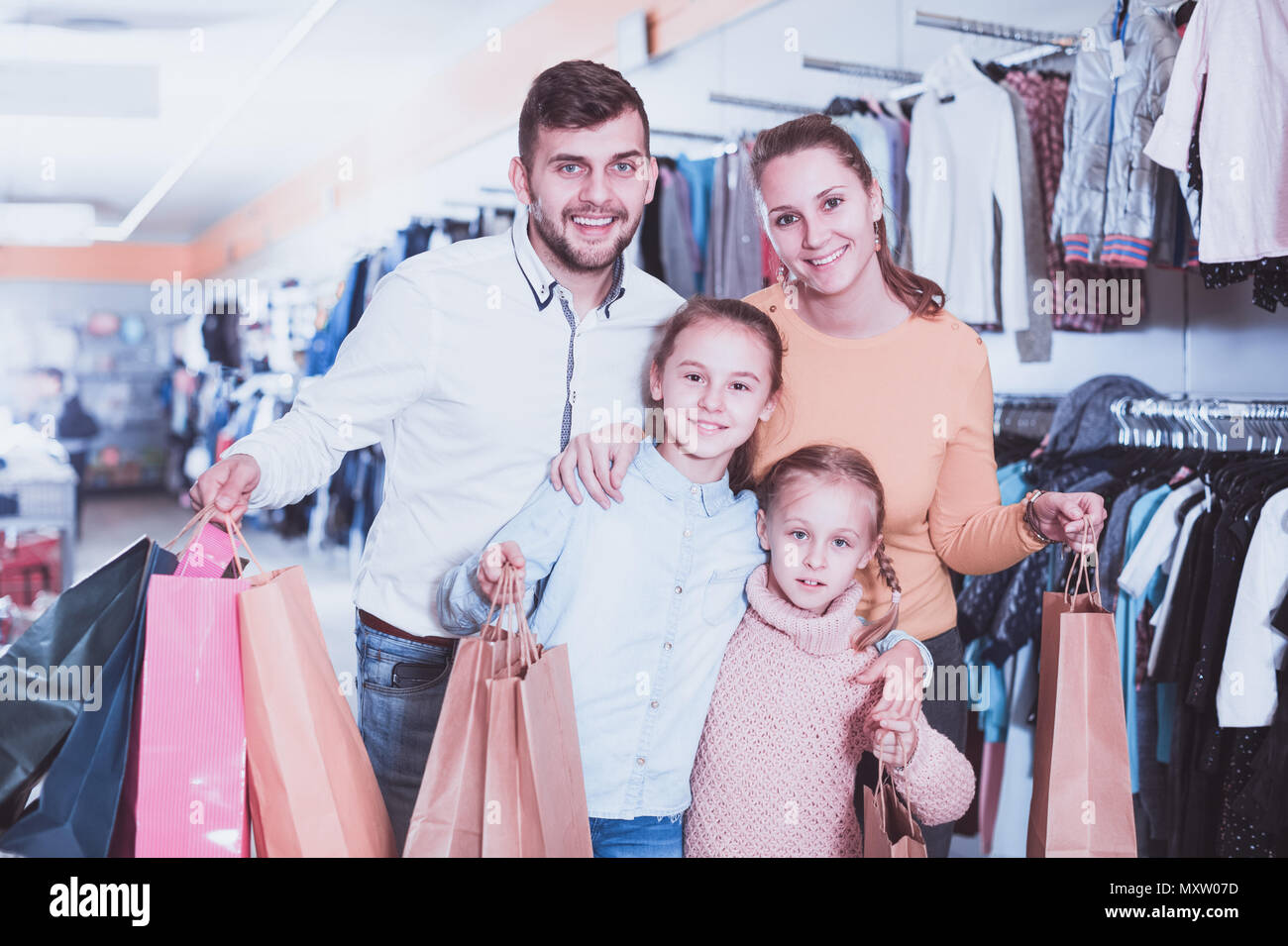 Young smiling family with two daughters after shopping in clothes store ...