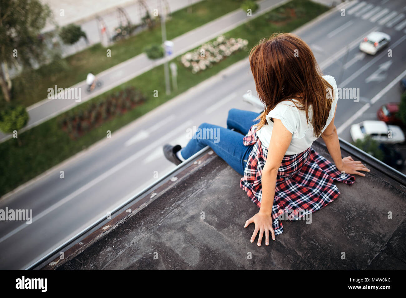 Young brown haired girl sitting on roof Stock Photo - Alamy