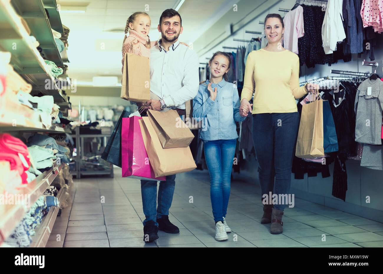 Ordinary family with two daughters walking in store after shopping ...