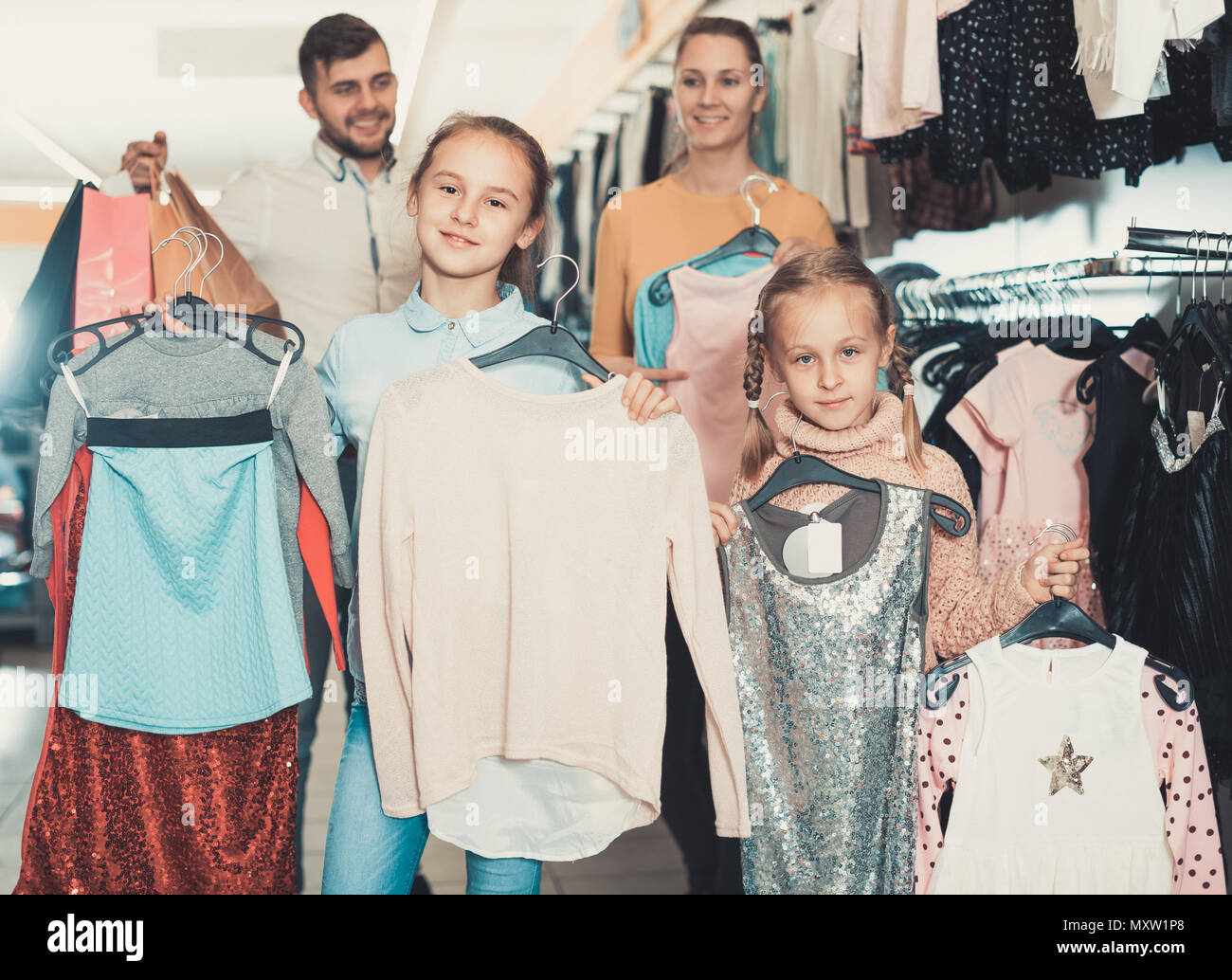 Two smiling little sisters with mum and dad during family shopping in ...