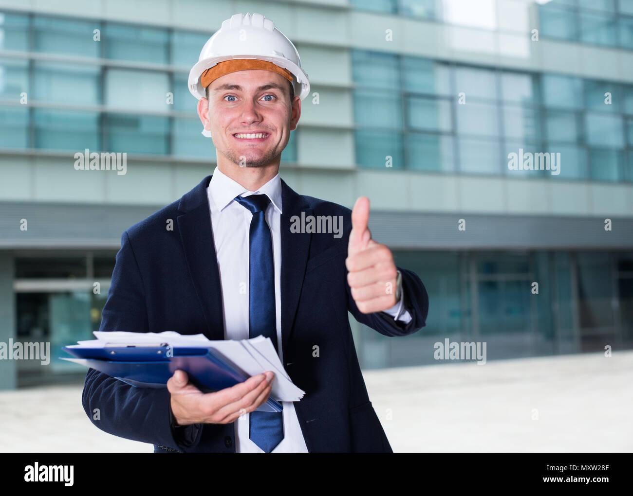 Engineer in suit and hat with folder is satisfied with realisation his ...