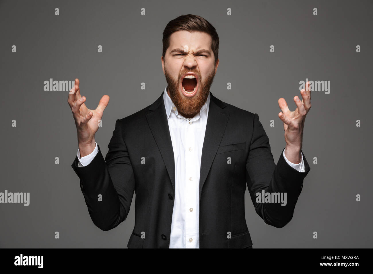 Portrait of an angry young businessman dressed in suit screaming ...