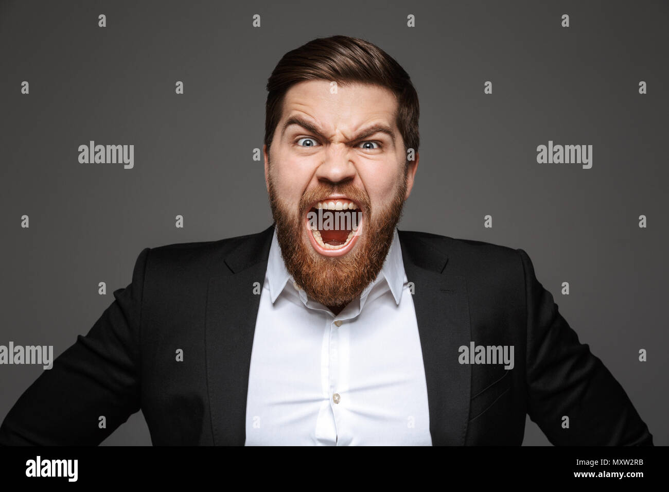 Portrait of a furious young businessman dressed in suit screaming ...
