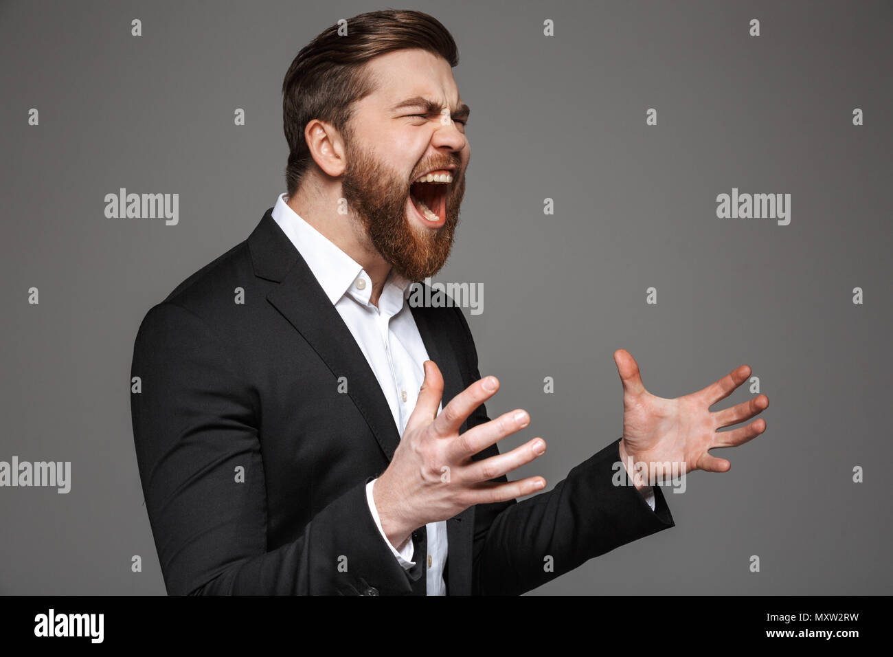 Portrait of an angry young businessman dressed in suit screaming away ...