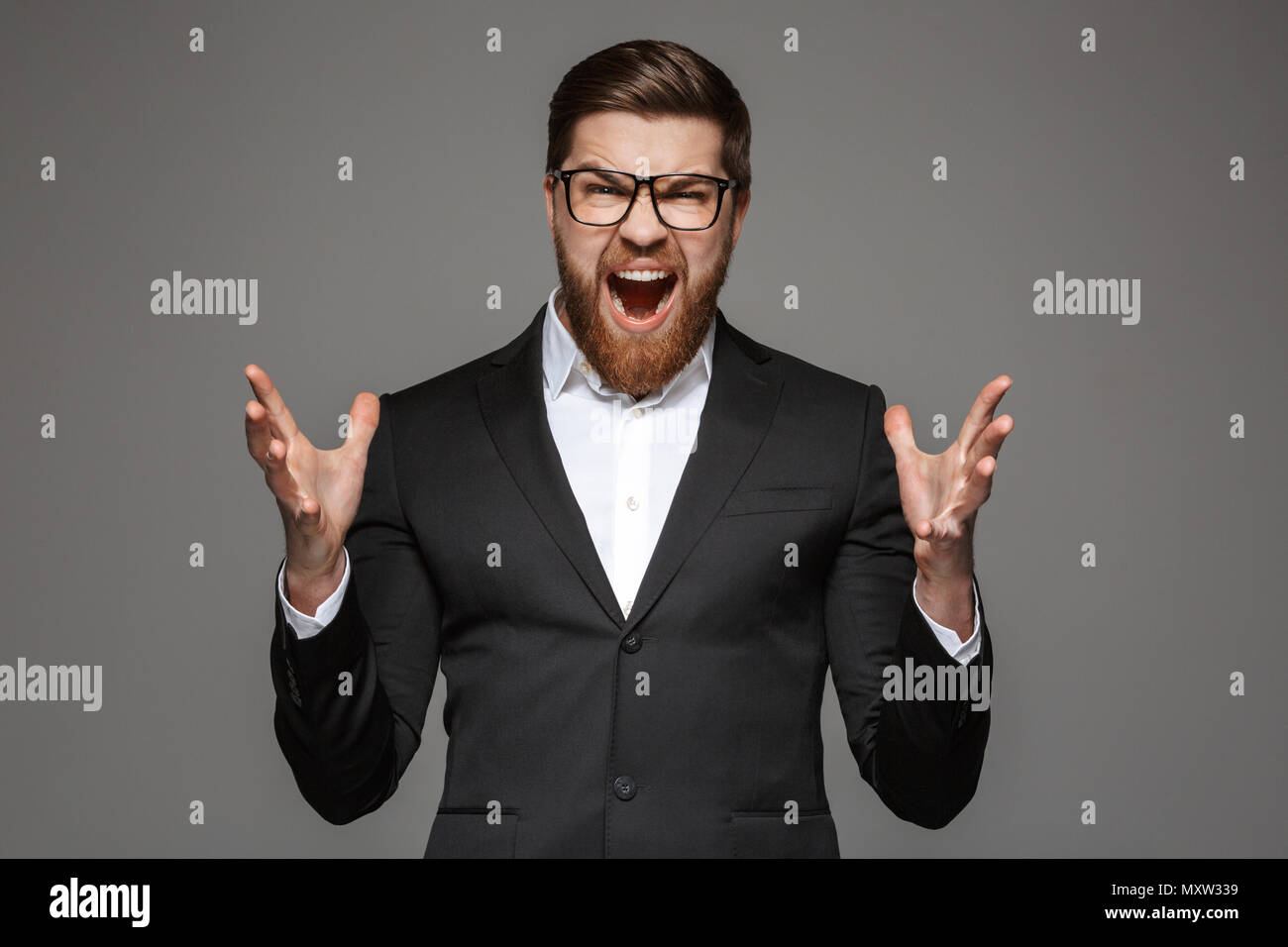 Portrait of an angry young businessman dressed in suit screaming ...