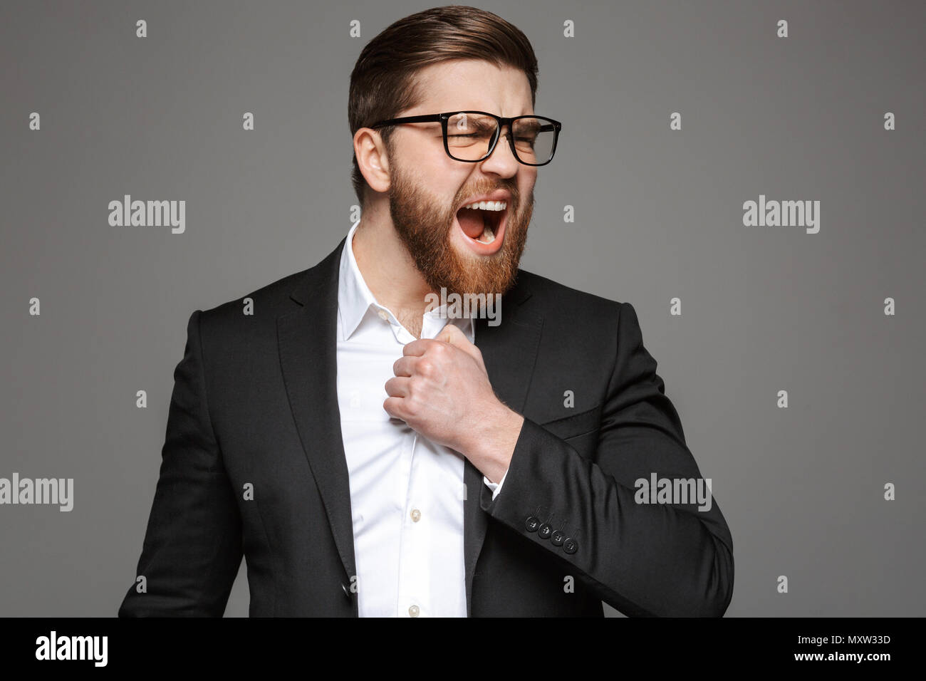 Portrait of an angry young businessman dressed in suit screaming away ...