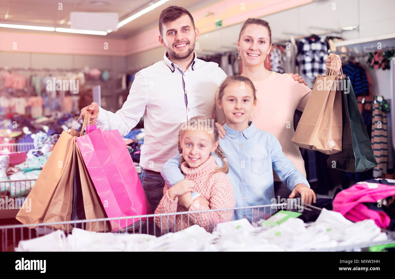 Young positive family with two daughters holding bags after shopping in ...