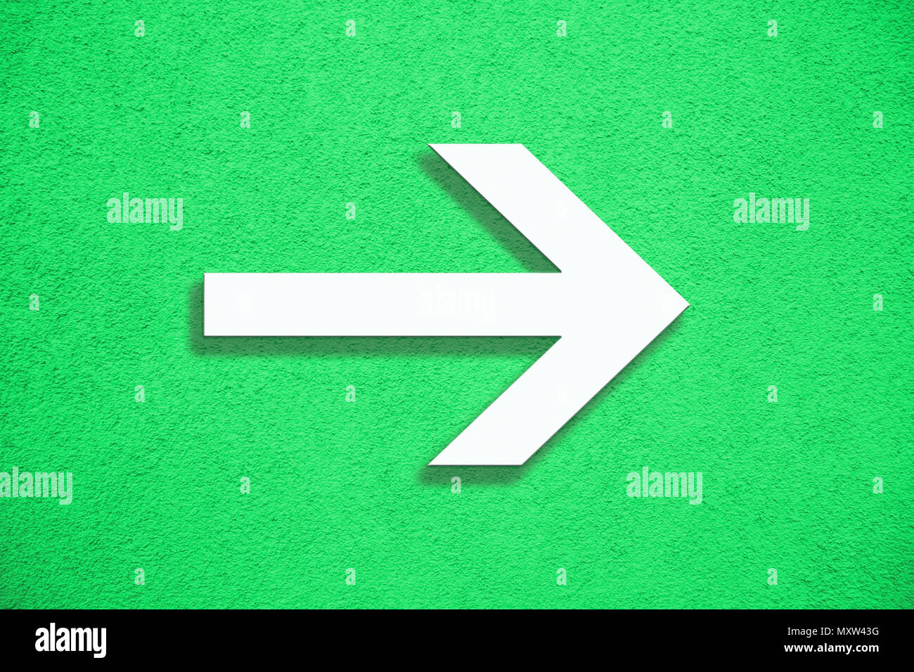White arrow direction sign over vivid bright green color stucco rough ...