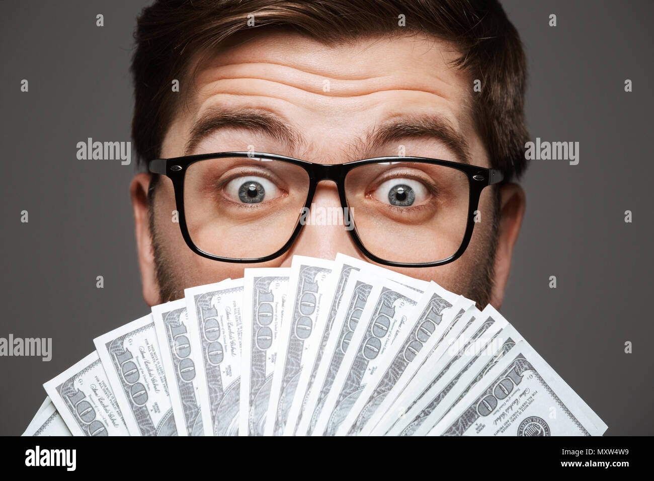 Close up portrait of a happy young businessman holding money banknotes ...