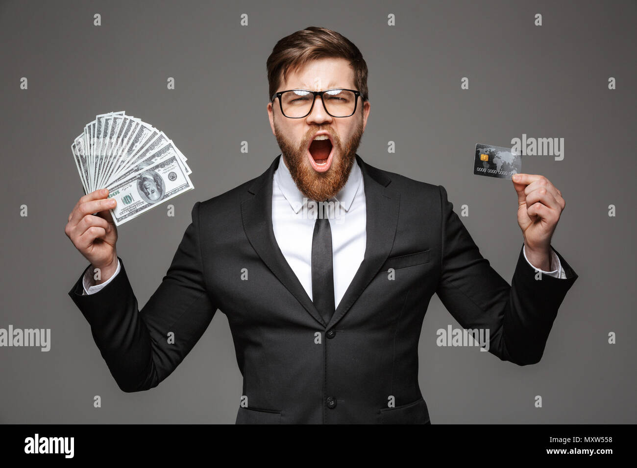 Portrait of a shocked young businessman holding money banknotes and ...