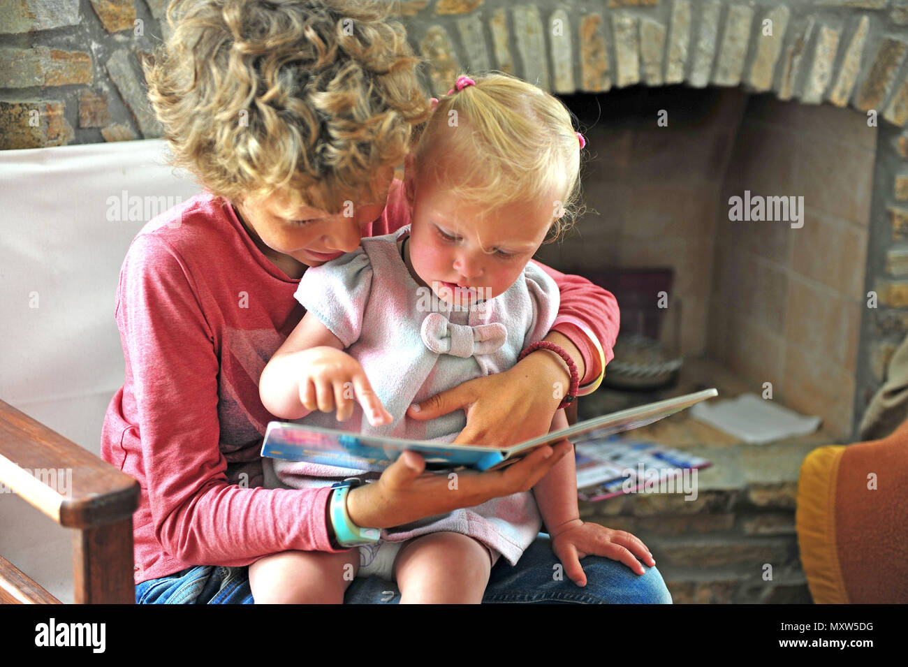 Brother reading book with his sister Stock Photo - Alamy