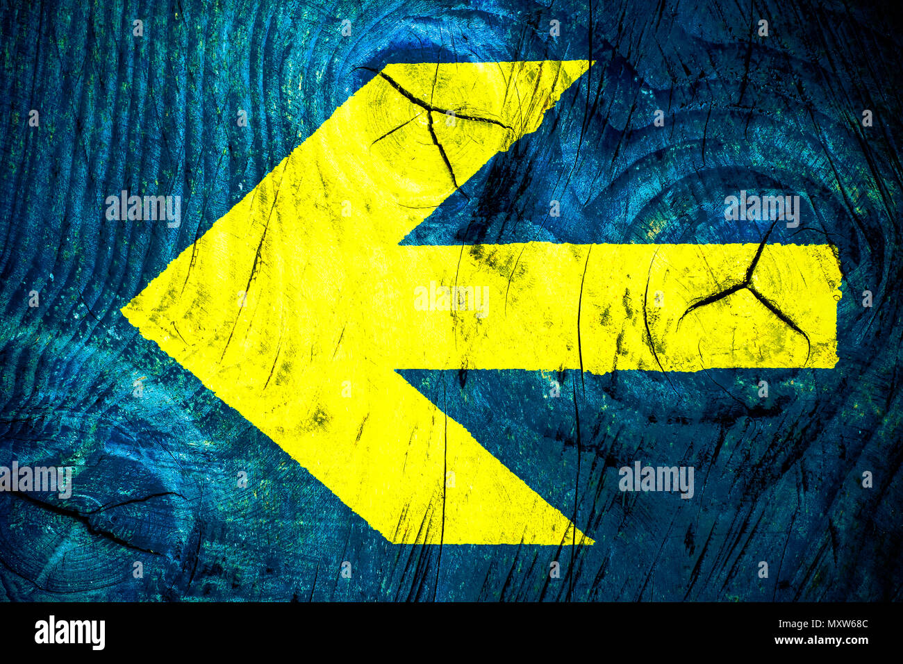 Yellow arrow direction sign over vivid bright blue color wooden wall ...