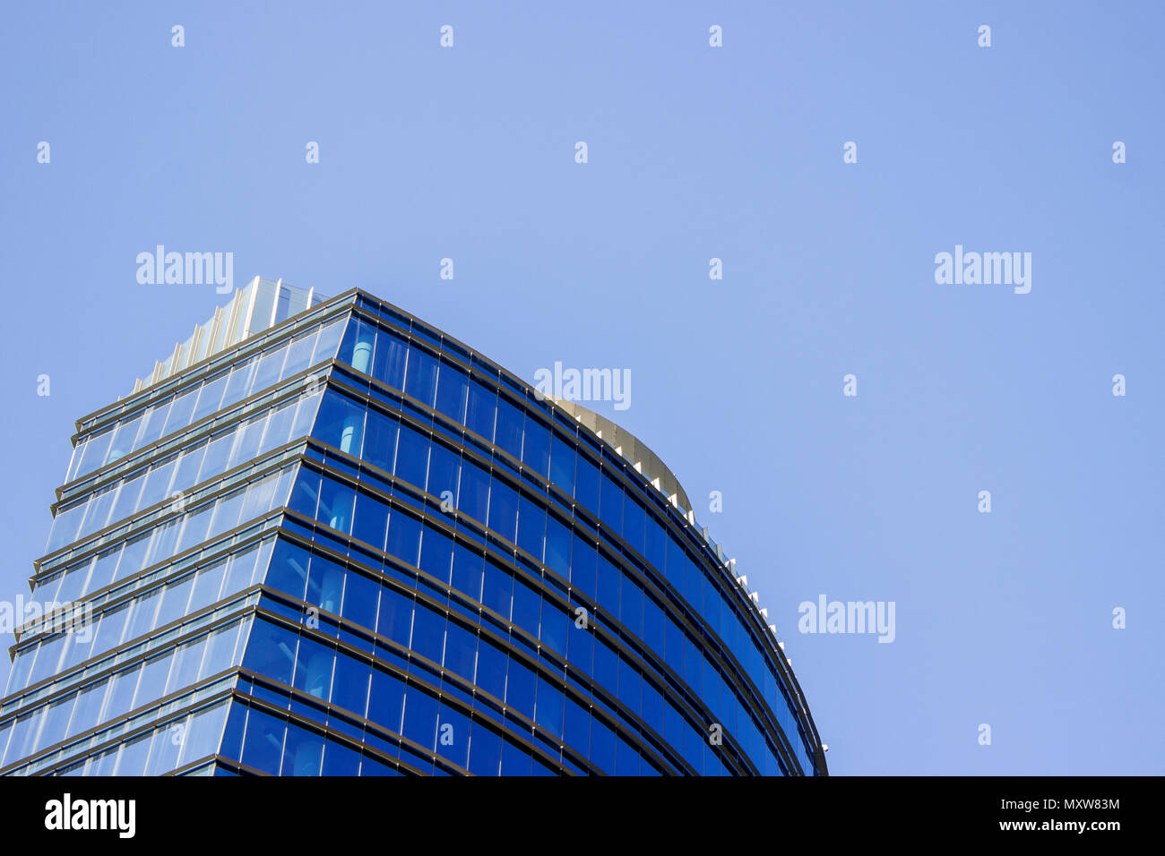 Top part of a blue modern corporate high-rise building with a striped ...