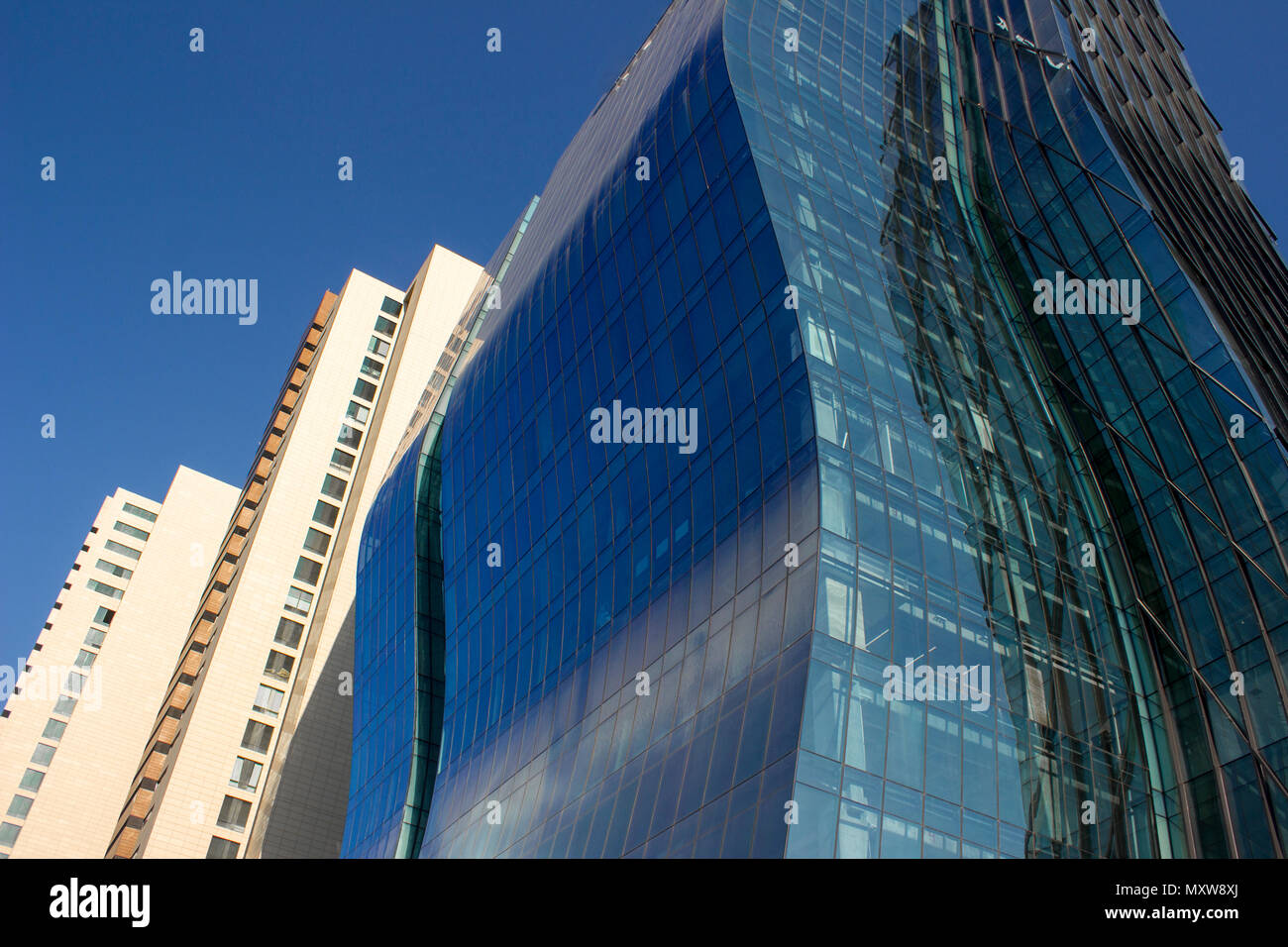 Wide view of a modern curved blue corporate building next to a ...