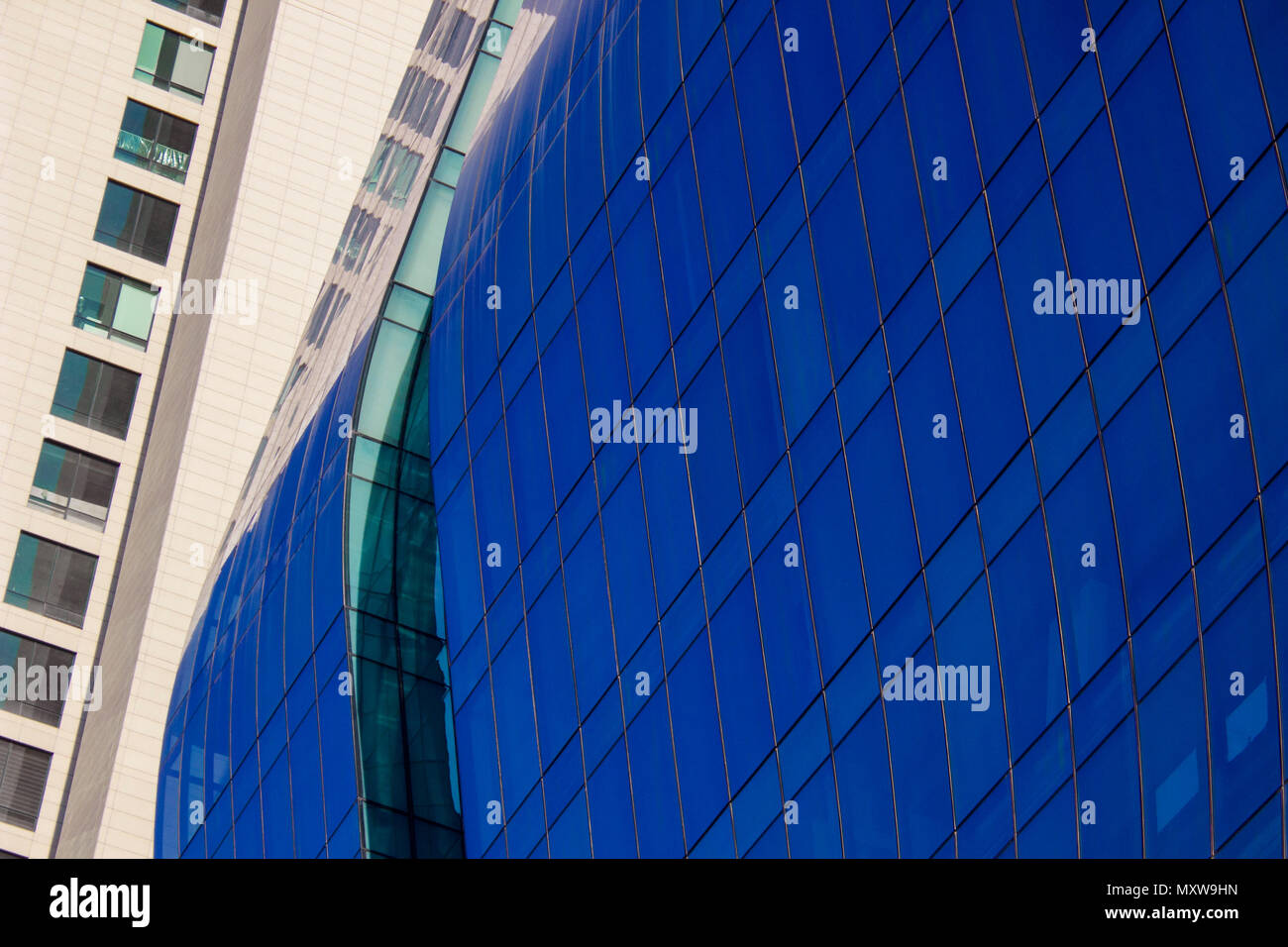 Close shot of a modern curved blue glass window wall next to a ...