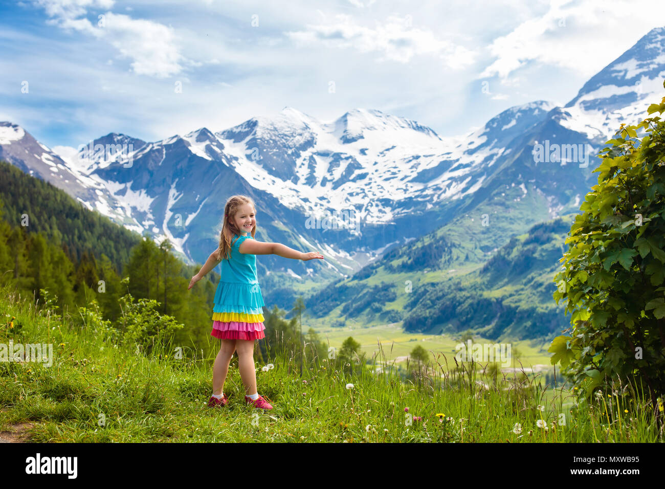 Children hiking in Alps mountains. Kids look at snow covered mountain ...
