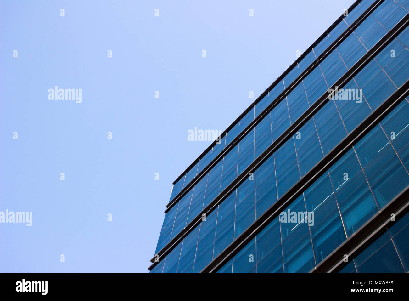 Side low angle view of a blue glass window wall of an office building ...