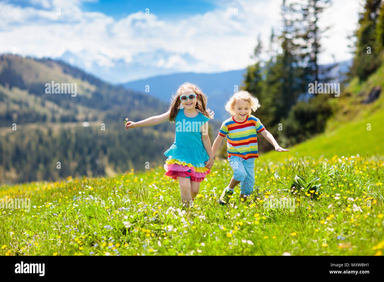 Children hiking in Alps mountains. Kids run at snow covered mountain in ...