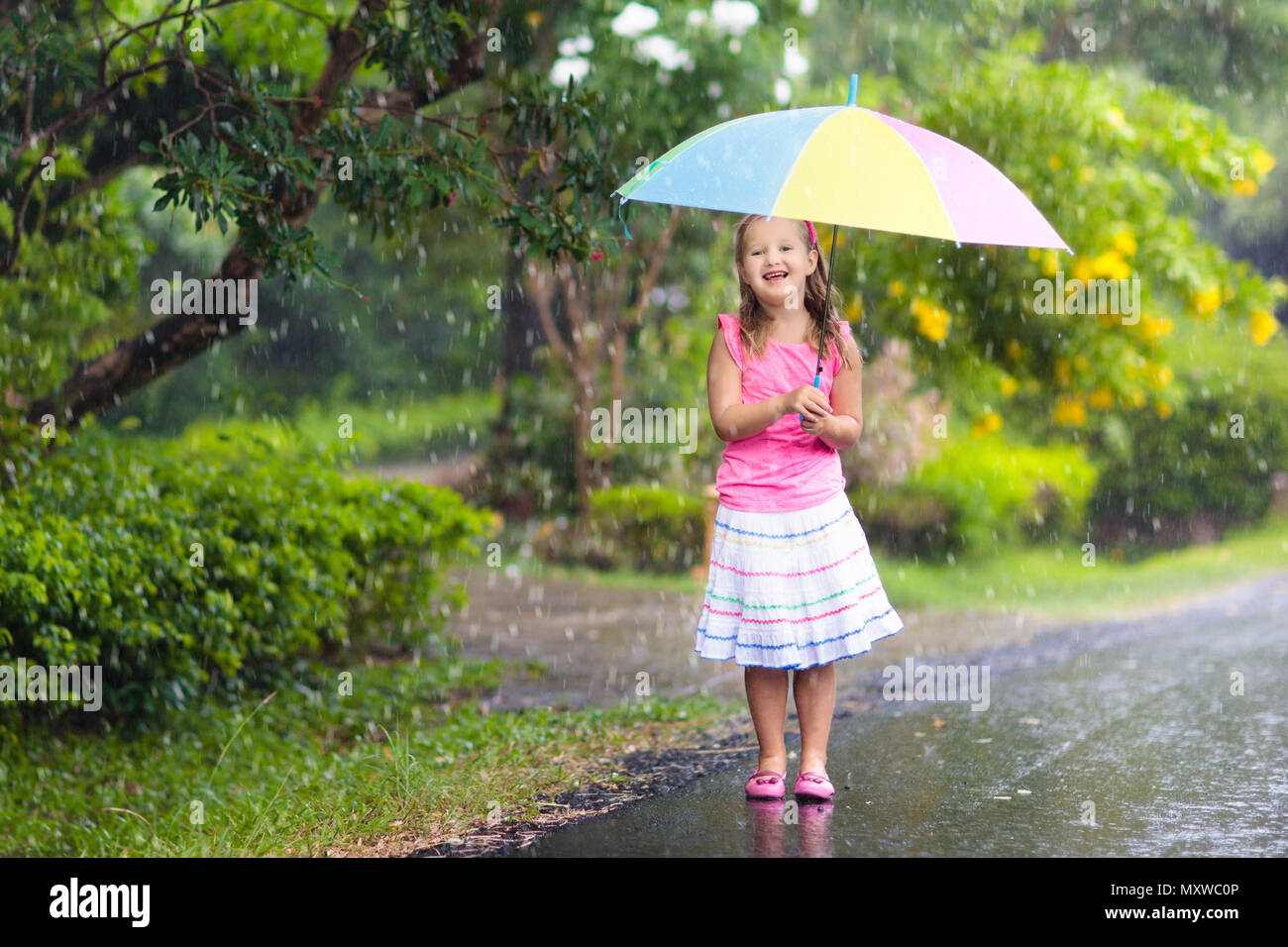 Kid playing out in the rain. Children with umbrella play outdoors in ...