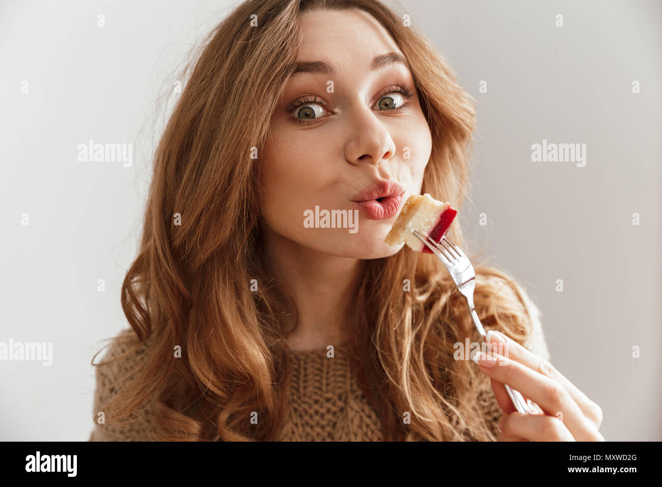 Image of beautiful woman wearing knitted sweater eating piece of cake ...