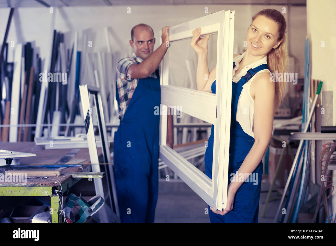 Portrait of two workers with plastic window frame in assembly shop ...