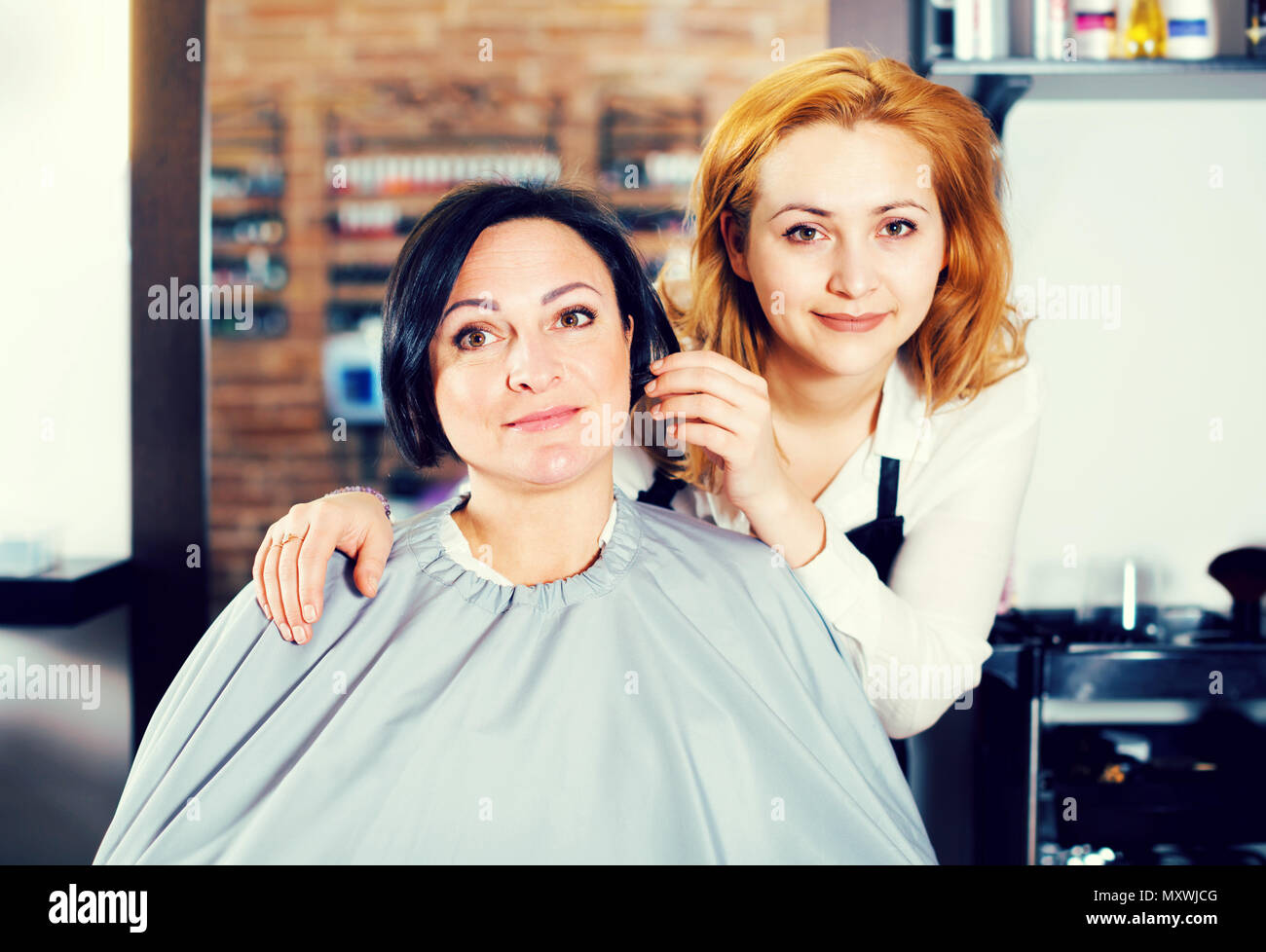Smiling woman in hairdressing salon decides with young master how to ...