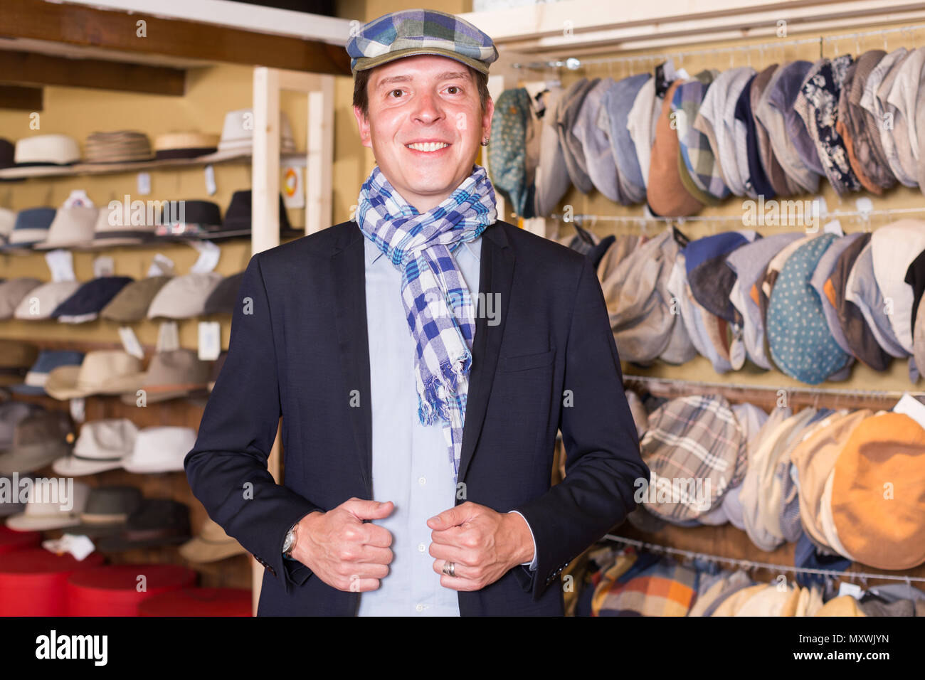 portret of positive young male try on newboy cap at the shopping mall ...