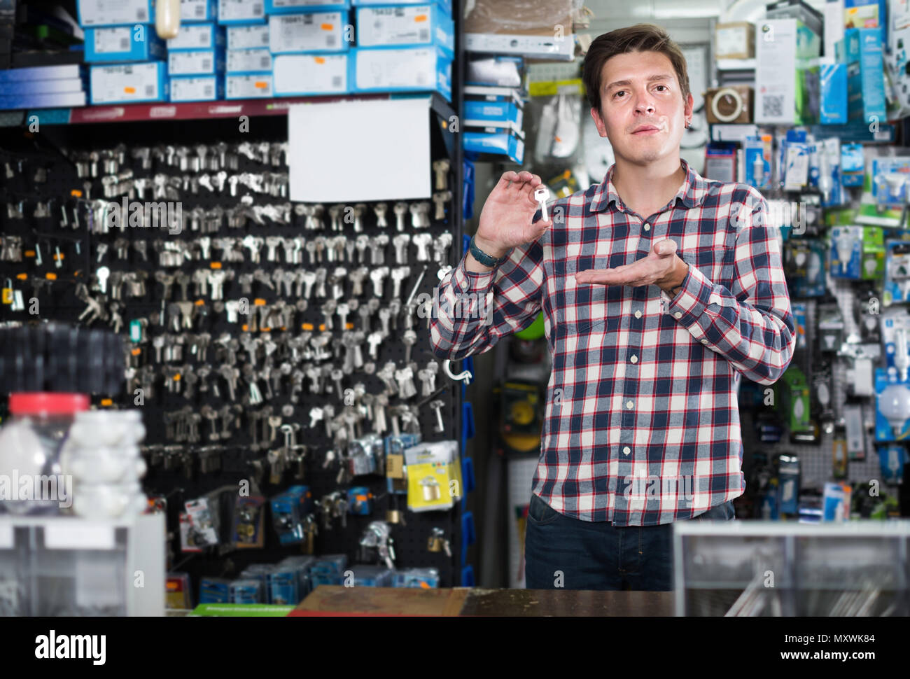 Positive employee with manufacturing keys in hardware store Stock Photo ...