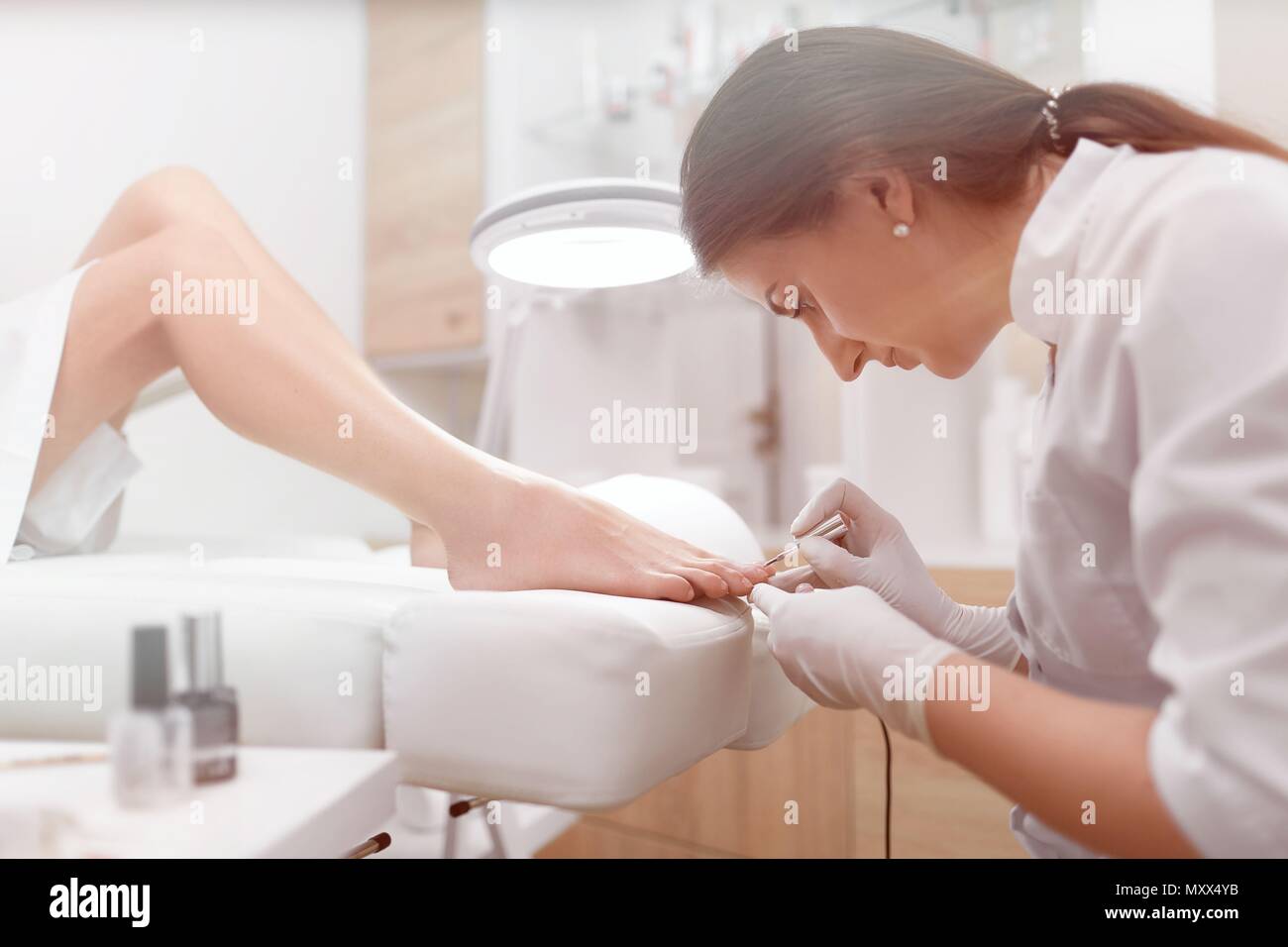 Podiatrist painting nails and making procedure for foot Stock Photo - Alamy