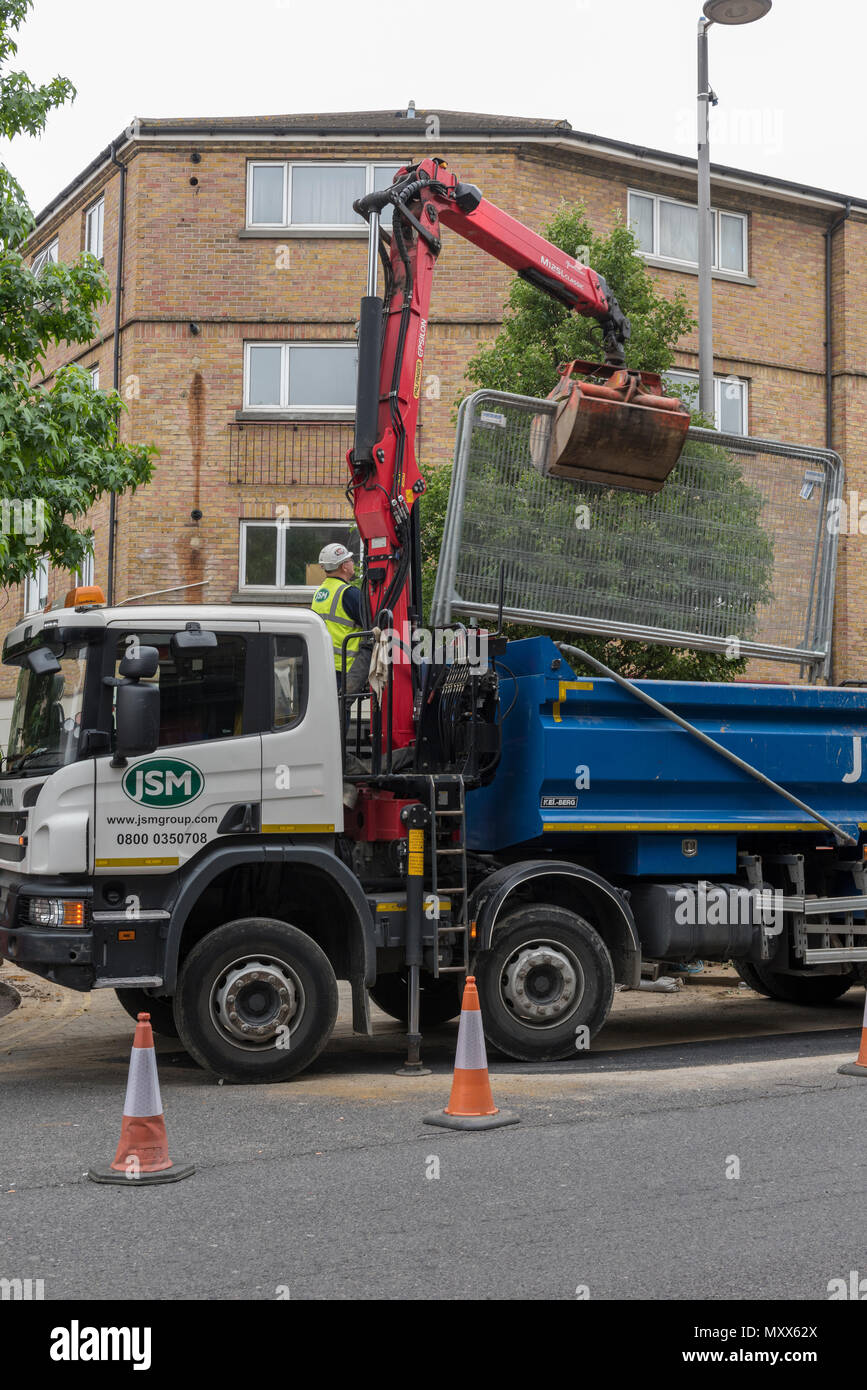 a roadworks lorry lifting herras fencing panels into the back usine a ...