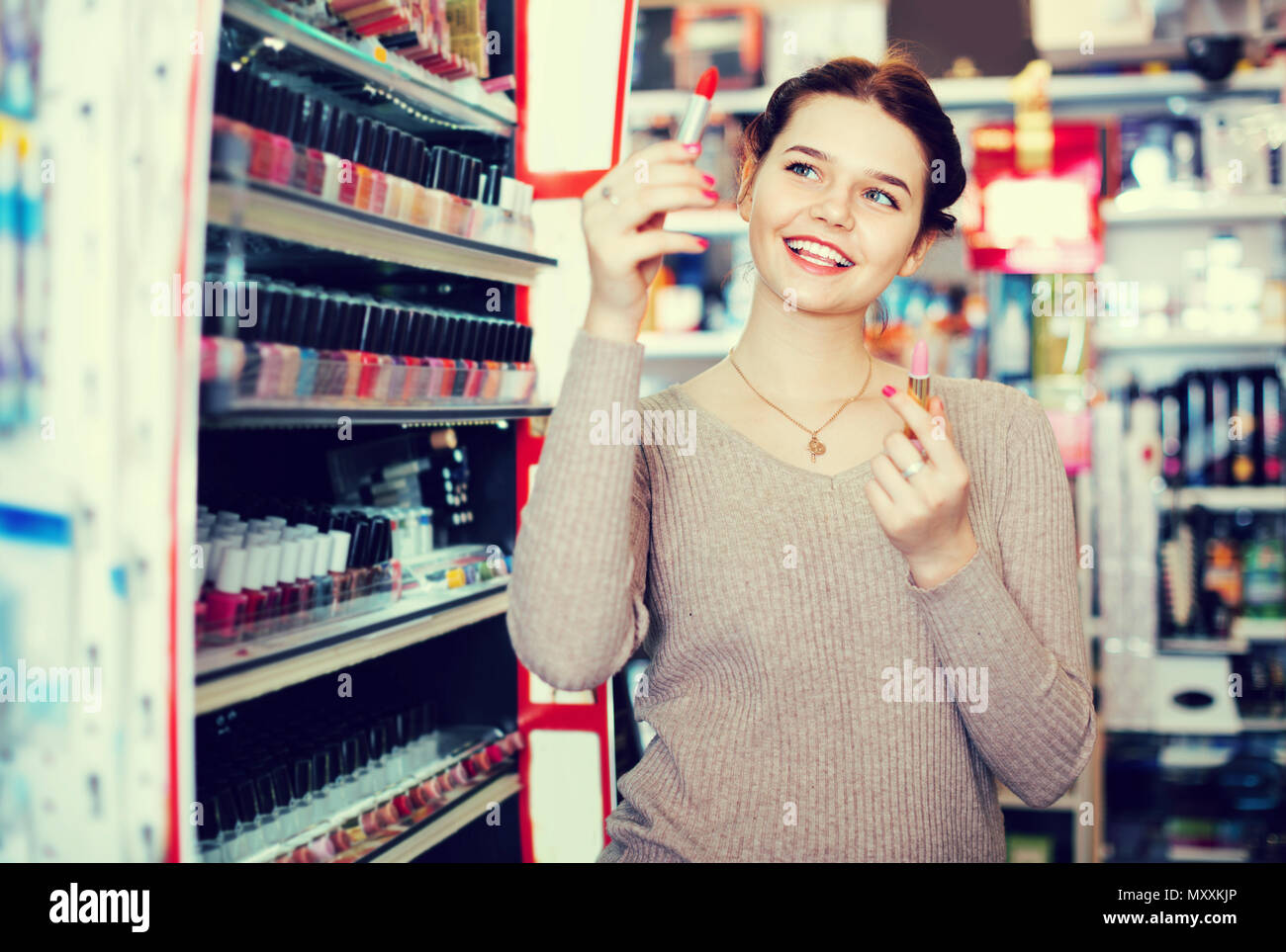 Happy cheerful positive woman customer browsing rows of lipstick in ...