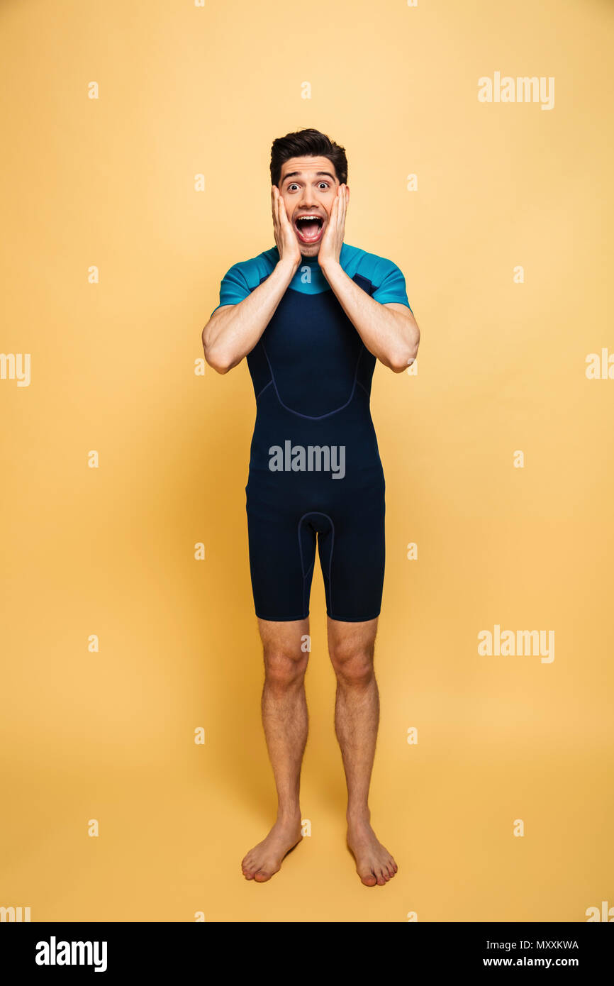 Photo of a shocked young man dressed in swimsuit isolated over yellow ...